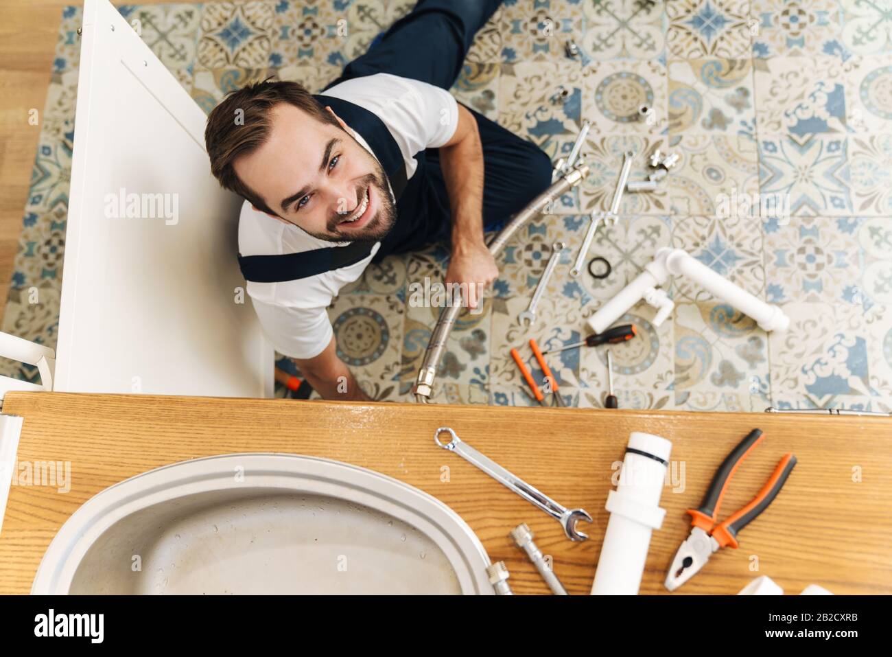 Image of a cheerful positive handsome young man plumber work in uniform ...