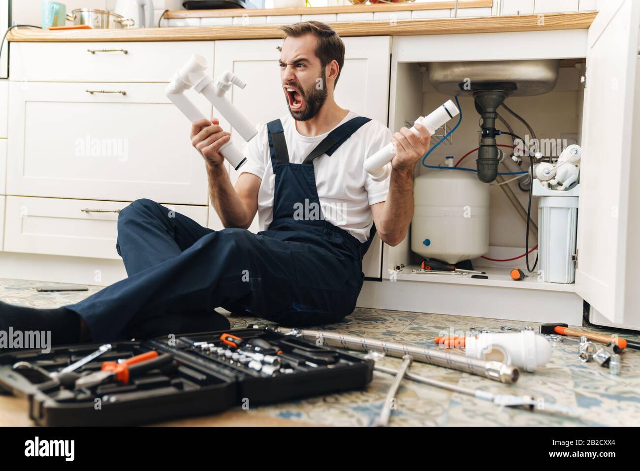 Photo of young screaming displeased emotional man plumber work in ...