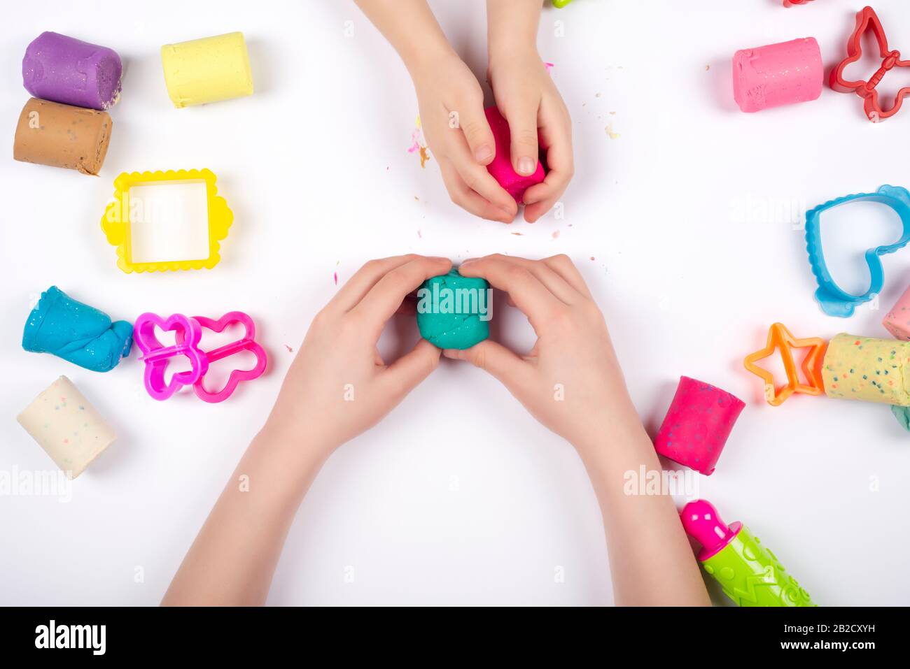 Children hands playing with colorful modeling clay on white background ...