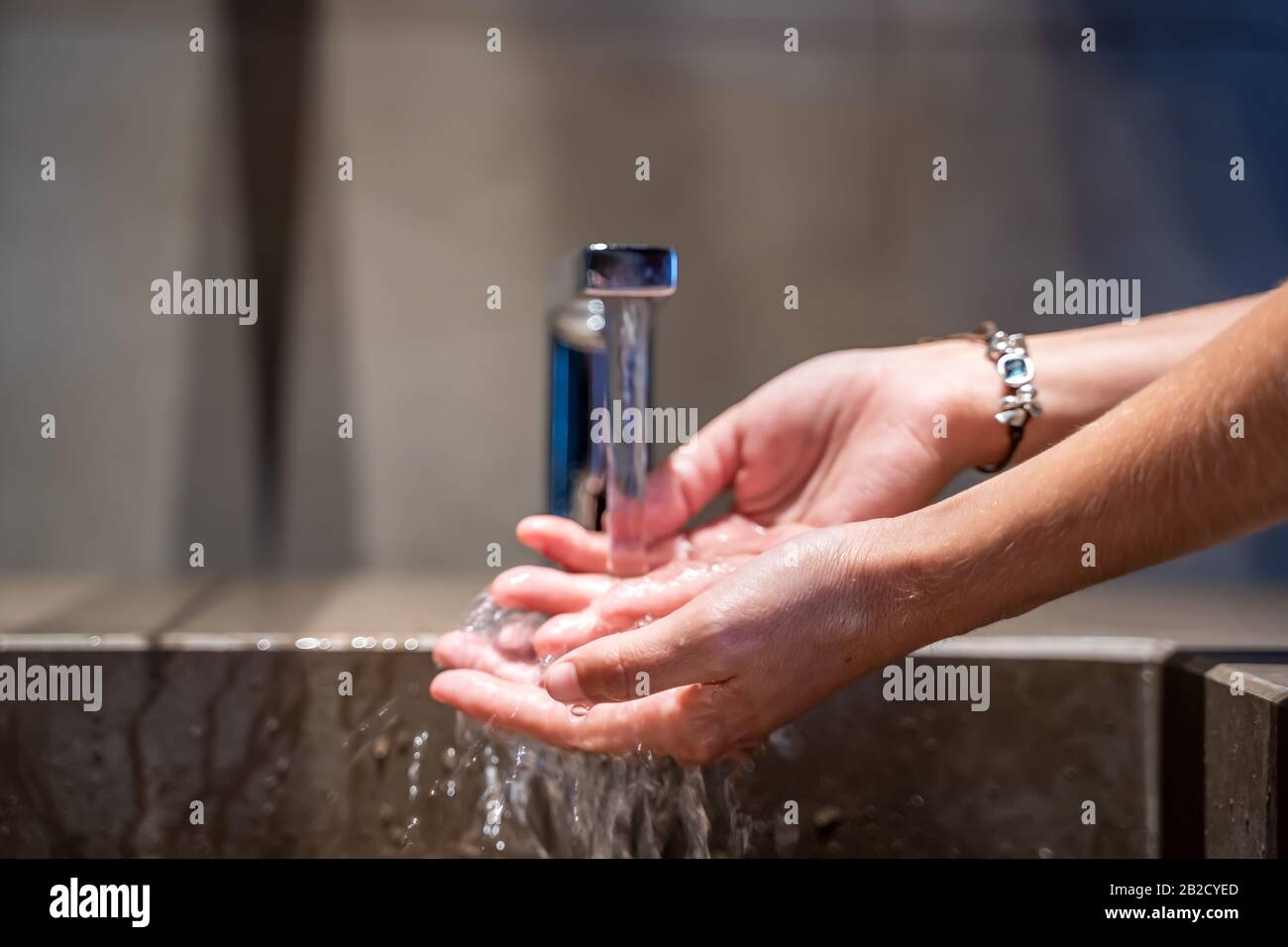 Hands of a girl with a ring washing in a sink of a bathroom with water ...