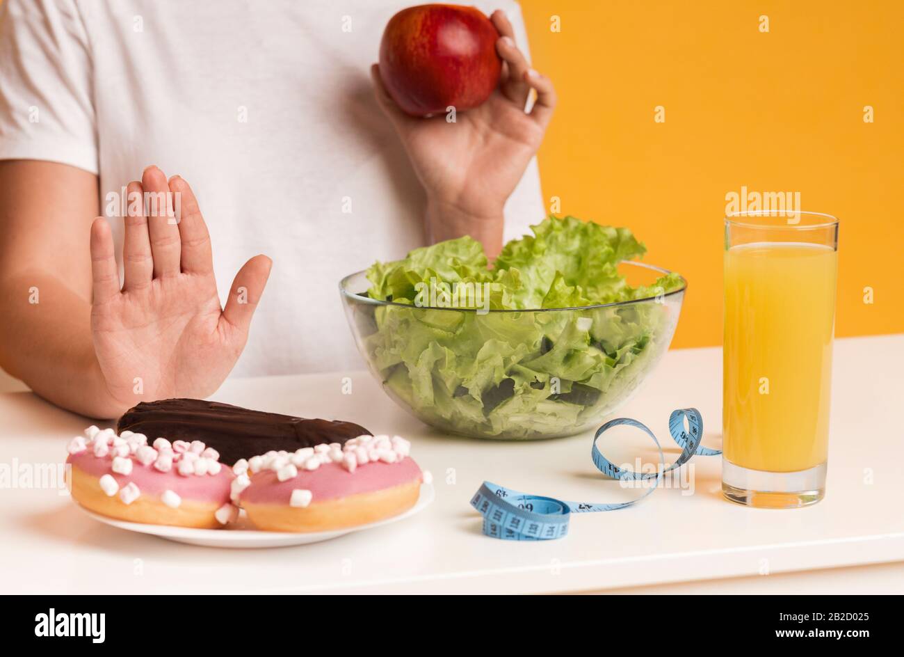 Unrecognizable woman rejecting junk food and choosing apple and salad ...