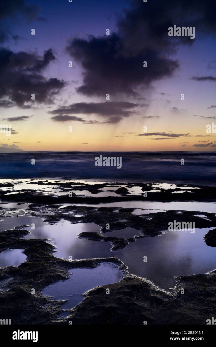 Dramatic sunset with rain showers falling from storm clouds over ocean ...