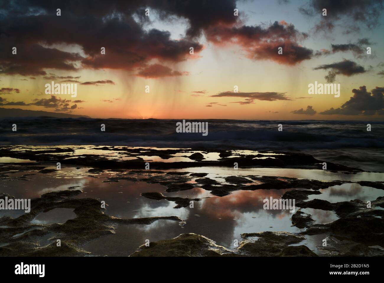 Dramatic sunset with rain showers falling from storm clouds over ocean ...