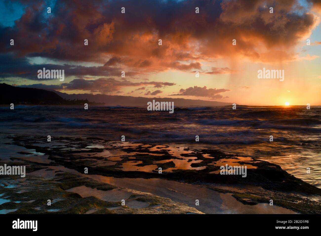 Dramatic sunset with rain showers falling from storm clouds over ocean ...