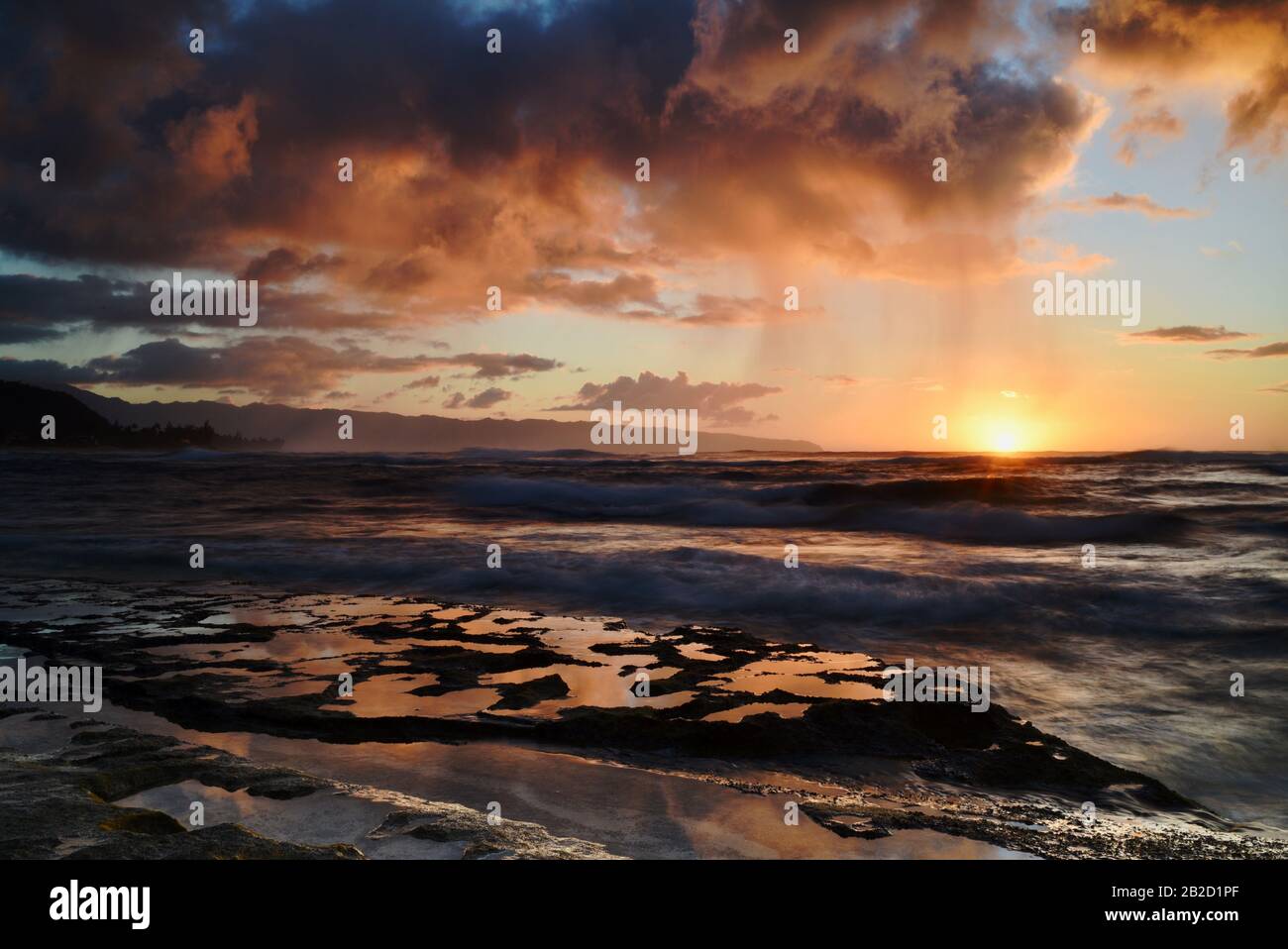 Dramatic sunset with rain showers falling from storm clouds over ocean ...