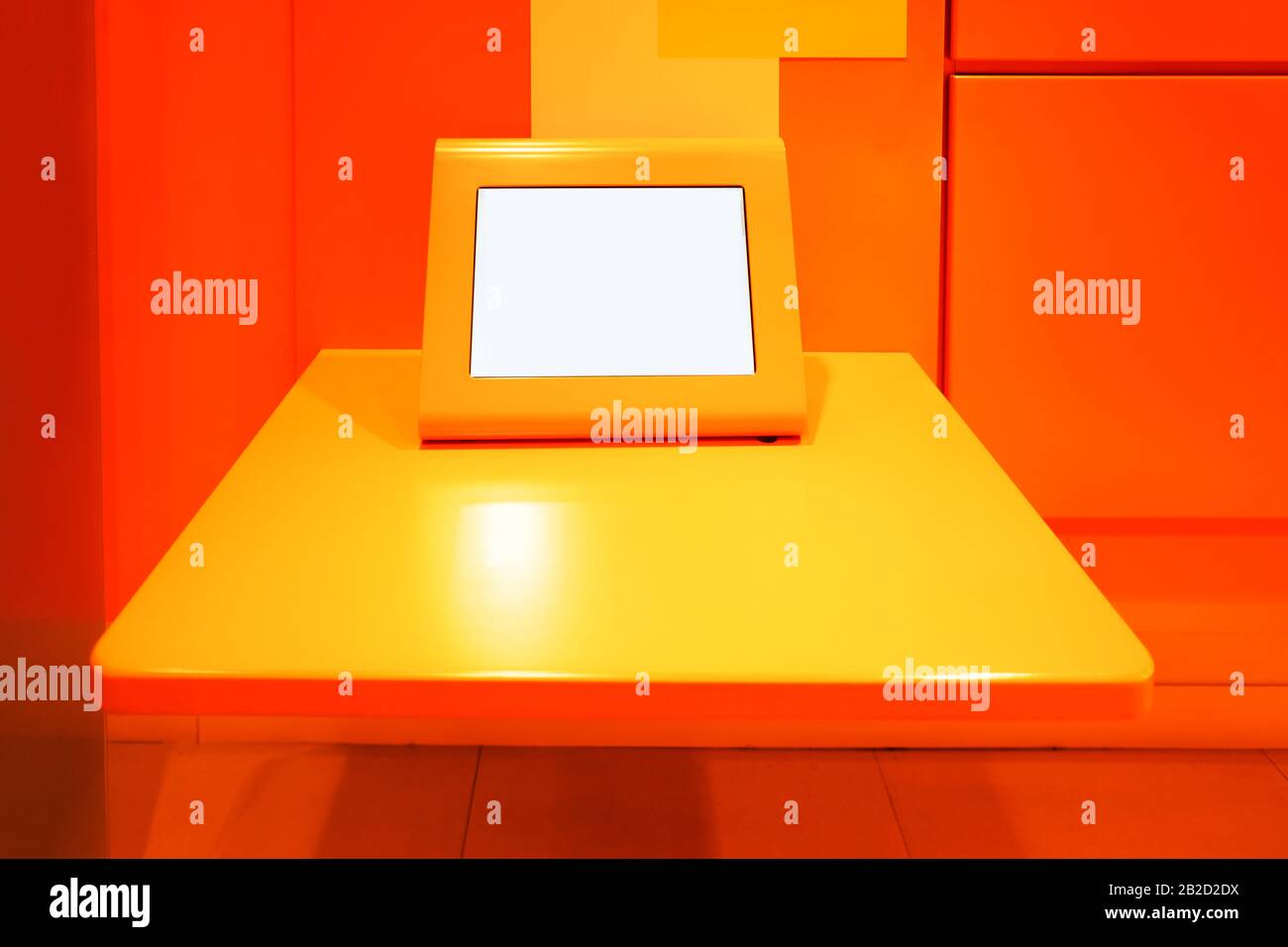 An office with orange tones design and a computer with blank screen ...