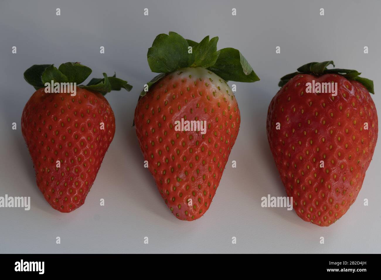 three strawberries isolated on white background Stock Photo - Alamy