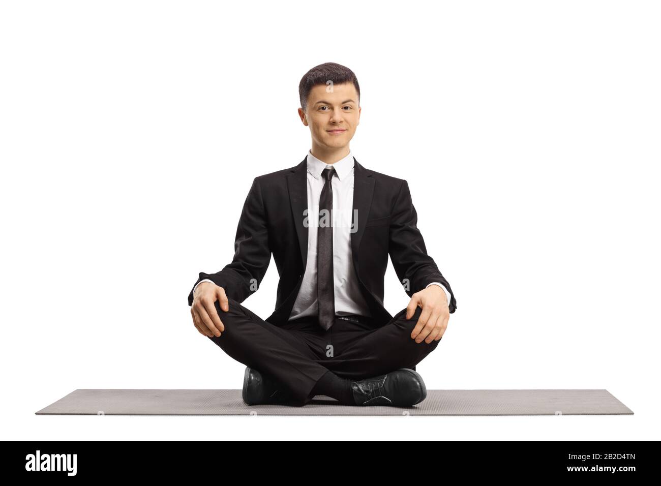 Young man in a black suit sitting with crossed legs and meditating on ...