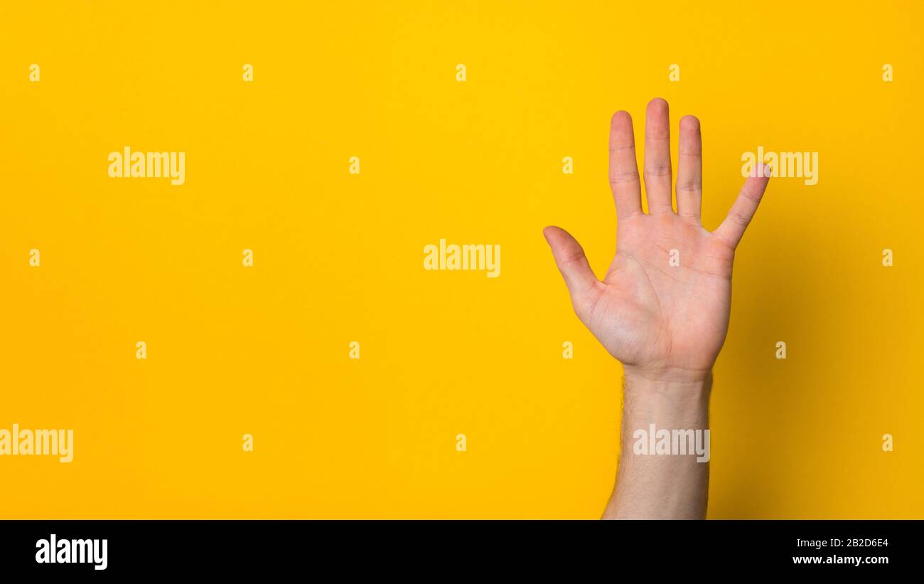 man hand up over a yellow background with copyspace for advert banner ...