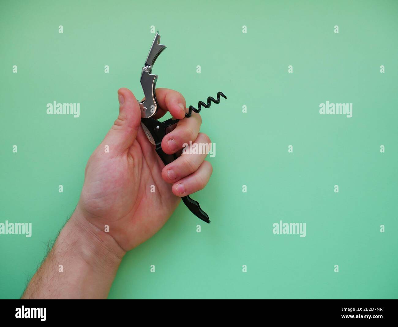 Mens hand holding metal corkscrew on colored background Stock Photo - Alamy