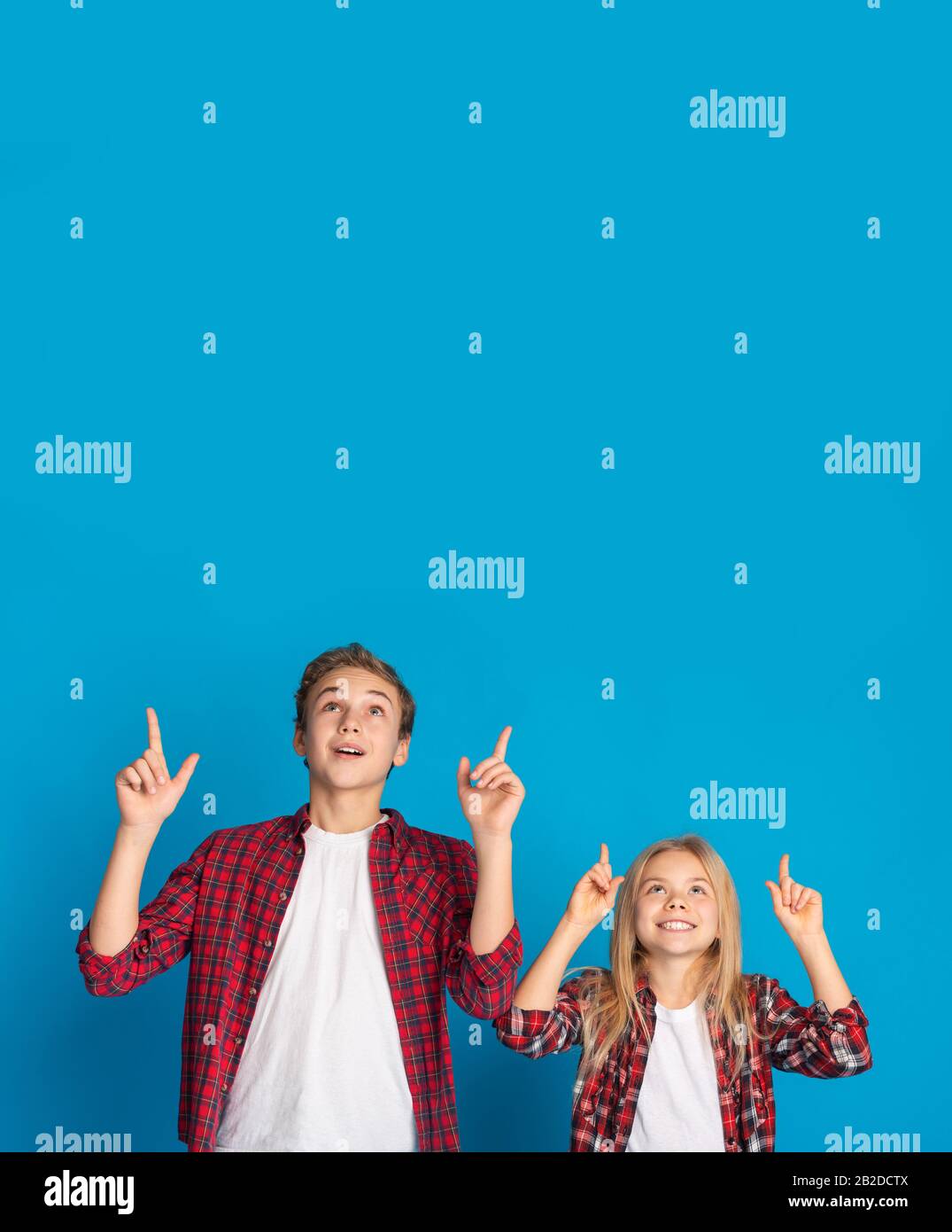 Little brother and sister pointing and looking upwards at copy space ...