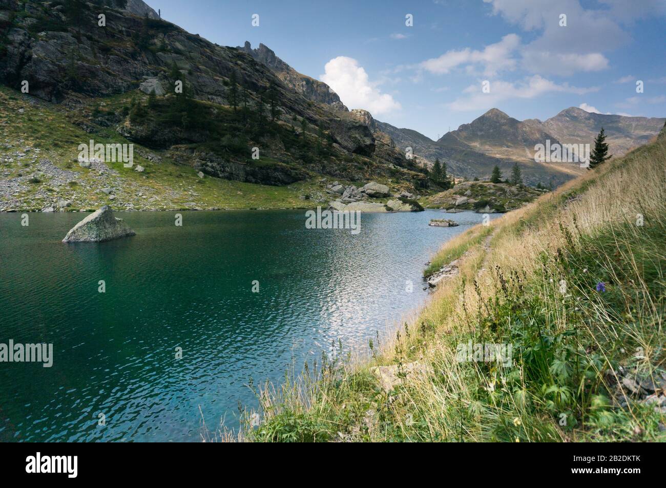 Hiking in summer Alps to blue lake of mountain Stock Photo - Alamy