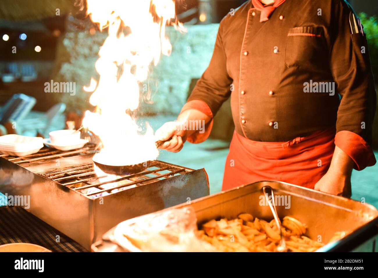 Cook cooks on fire at night Stock Photo - Alamy