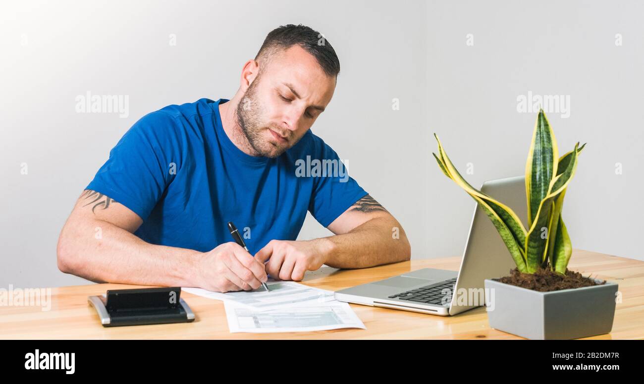 Man filling 1040 US tax form by hand with calculator and laptop Stock ...