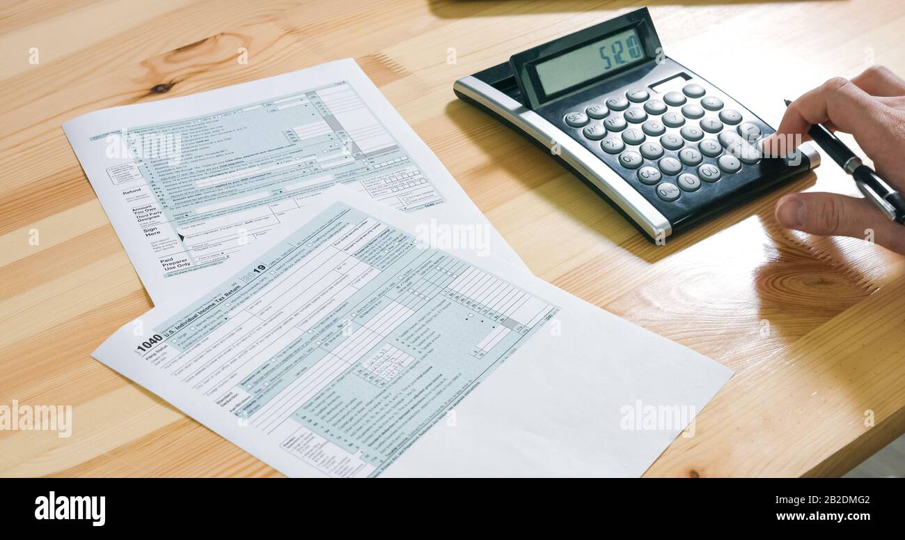 Closeup of US tax form 1040 and hand calculating and filling report ...