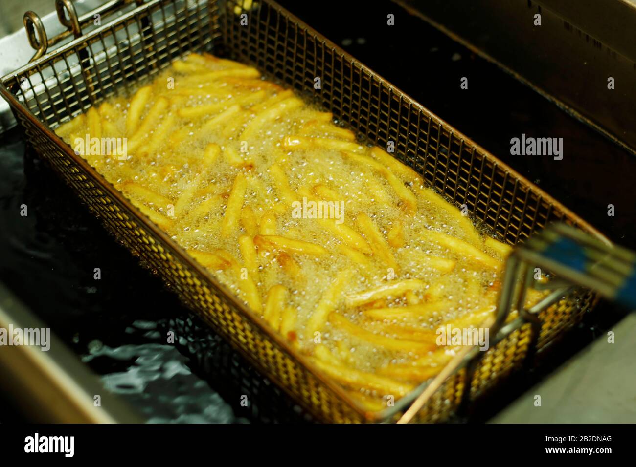 crispy french fries in a deep fat fryer with steel net basket Stock ...