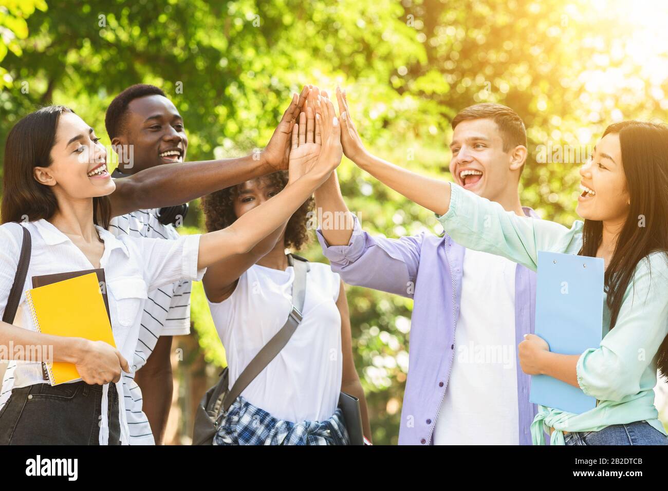 Happy international college students joining their hands together ...