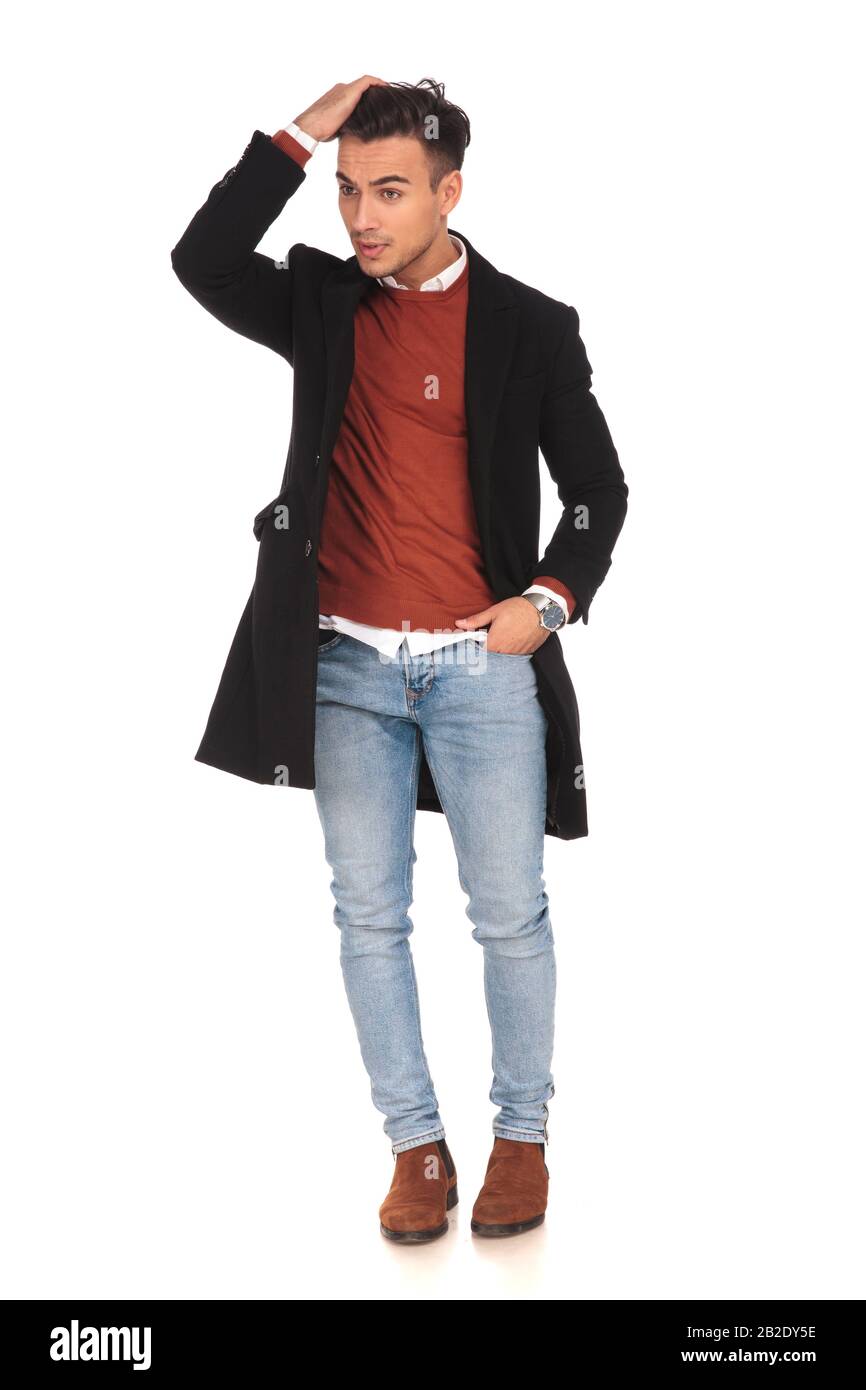 young man fixing his hair and looks away to side on white background ...