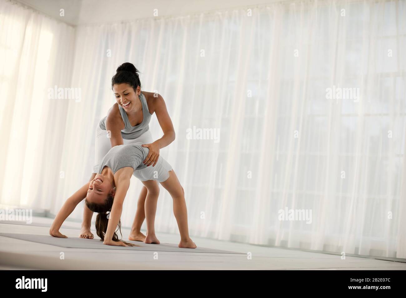Smiling mid adult woman helping a young girl with a yoga pose Stock ...
