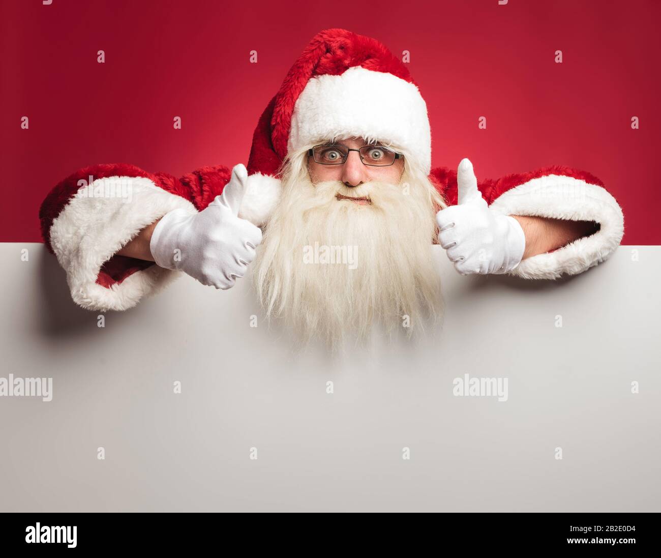 santa claus making the ok sign on top of a blank board on red ...