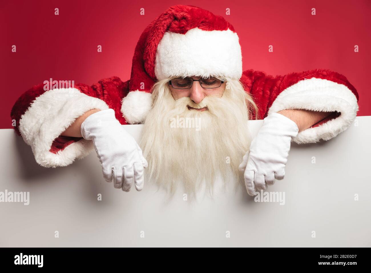 santa claus leaning on a big blank board and he looks downt at it on ...