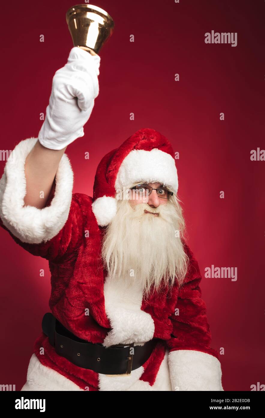 santa claus ringing his bell with hand in the air on red background ...