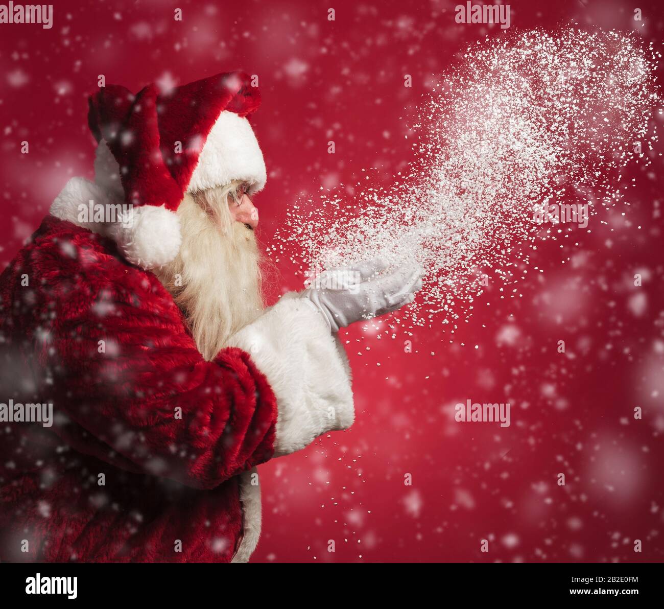 santa claus blowing snow from his hands on red background, side view ...