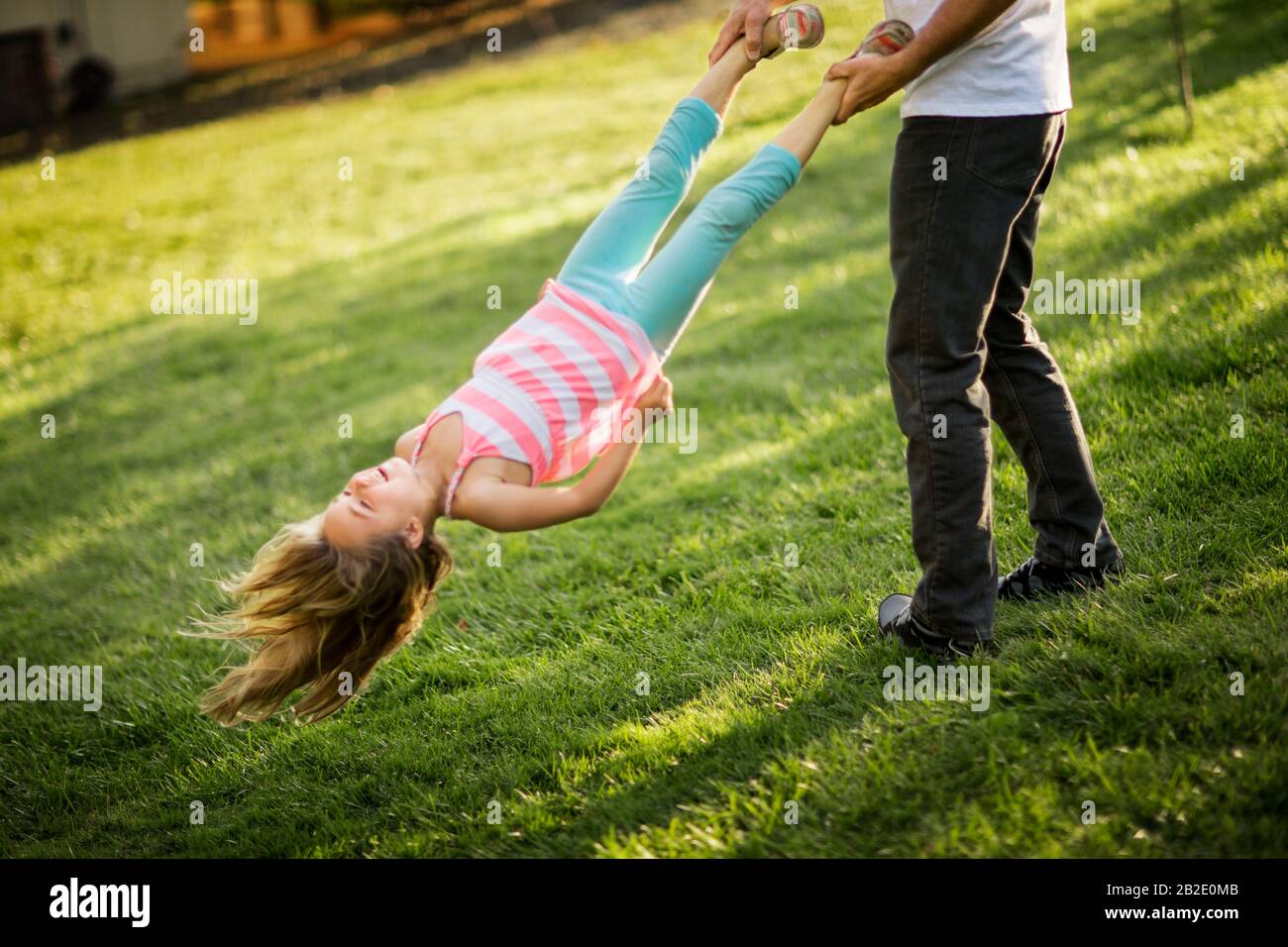 Mid adult man playfully spinning his happy young daughter around in the ...