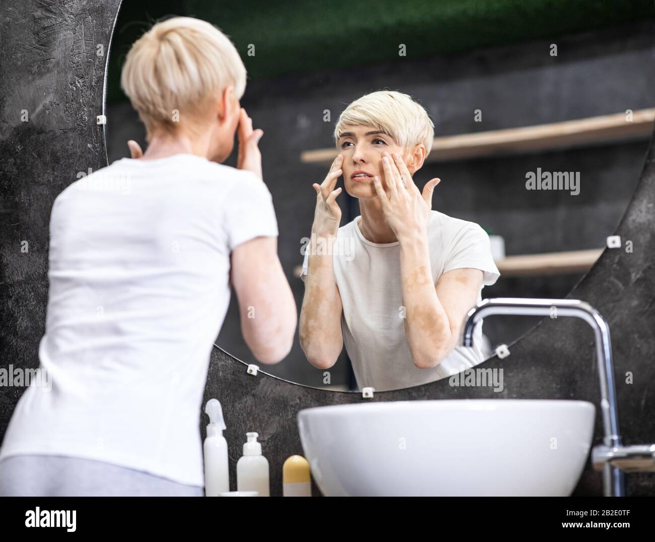 Mature Woman Looking At Wrinkles Under Eyes Standing In Bathroom Stock ...