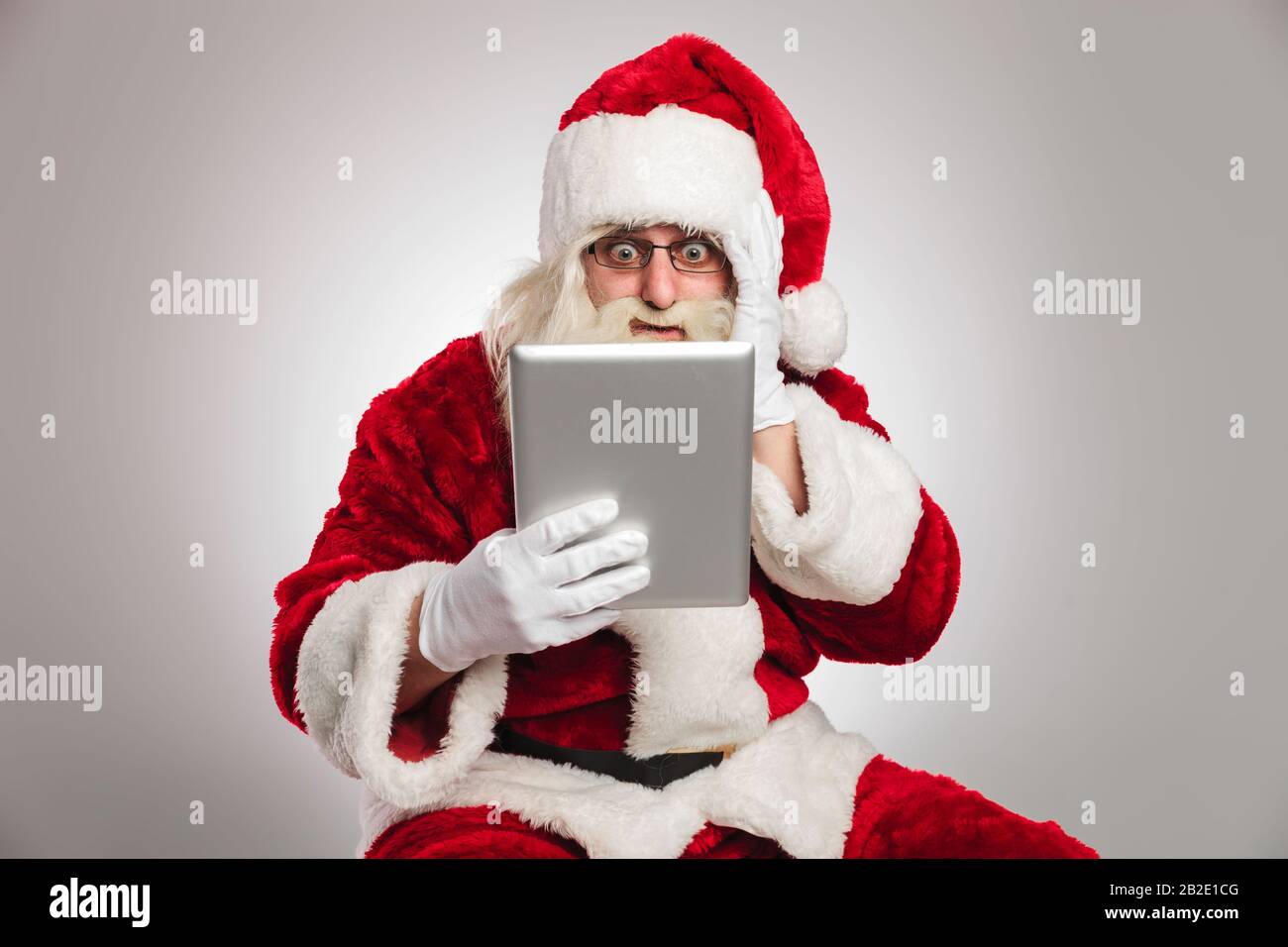 santa claus is reading something shocking on his tablet pad computer on ...