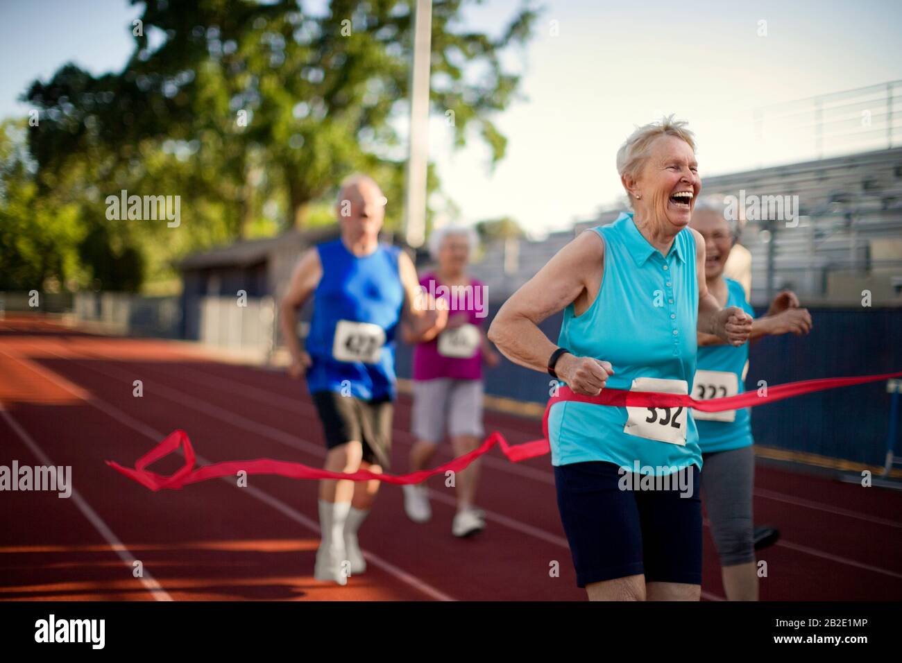 Happy senior woman crosses the finish line first in a running race ...