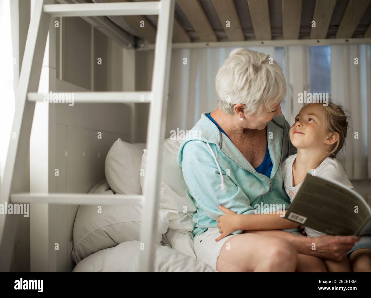 Smiling grandmother reading a story to her granddaughter Stock Photo ...