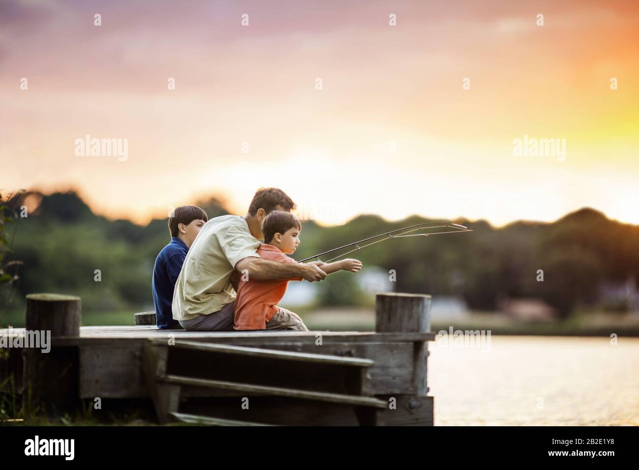 A father and his two sons fishing from a dock Stock Photo - Alamy
