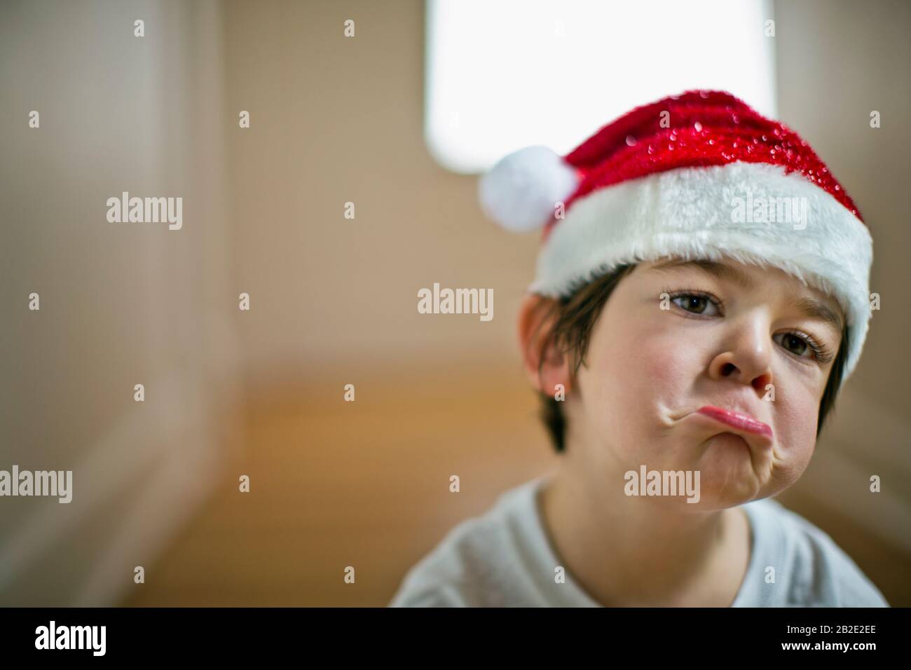 Pouting young boy wearing a Santa hat Stock Photo - Alamy