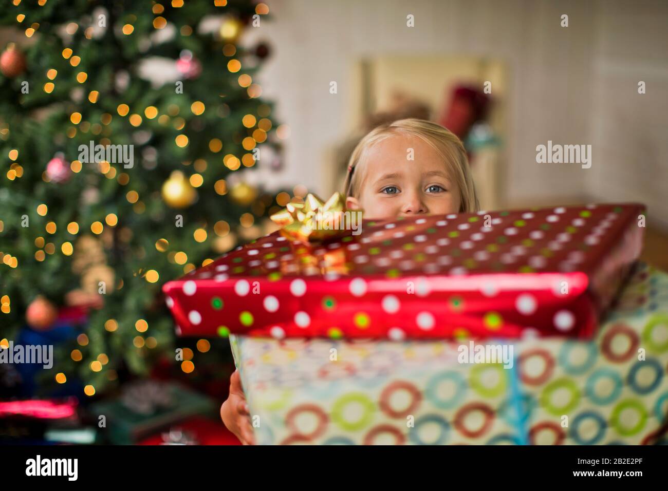 Young girl carrying a stack of Christmas presents Stock Photo - Alamy