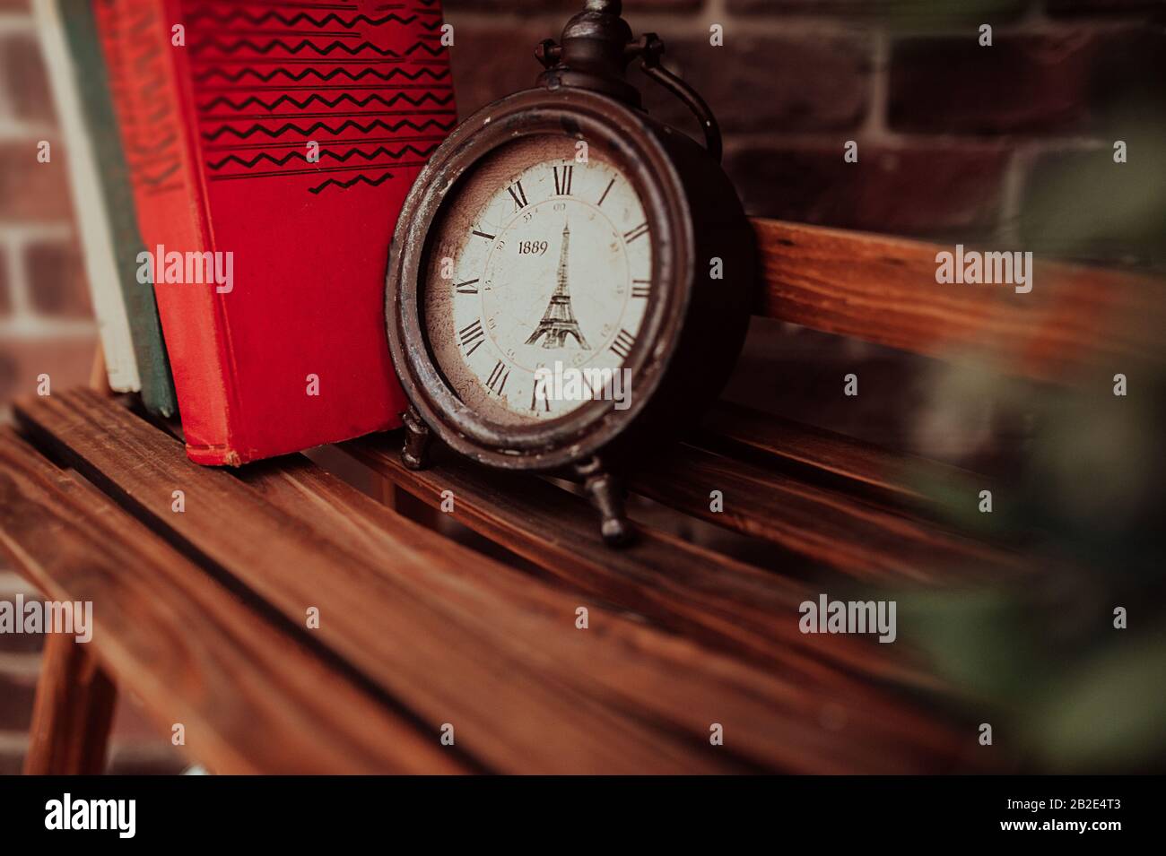 Old Antique Broken Clock Without Arrows With The Image Of The Eiffel Tower In A Wooden Bookcase old-antique-broken-clock-without-arrows-with-the-image-of-the-eiffel-tower-in-a-wooden-bookcase