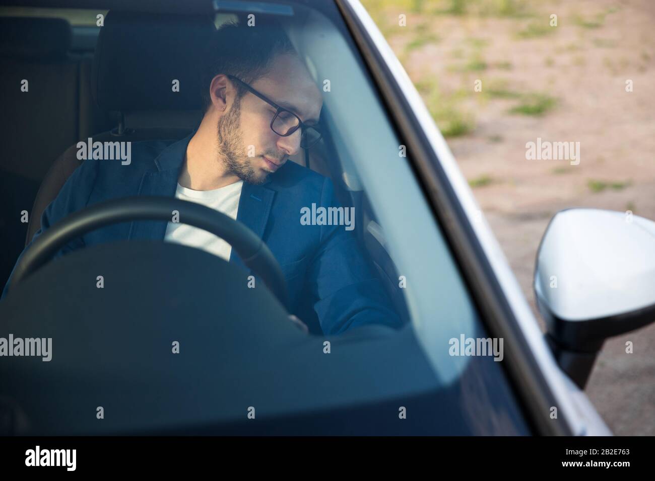 Tired business man falling asleep sitting inside her car seen through ...