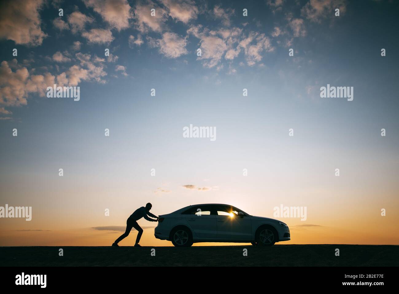 Silhouette of man driver pushing his car along on an empty road after ... Silhouette of man driver pushing his car along on an empty road after ...