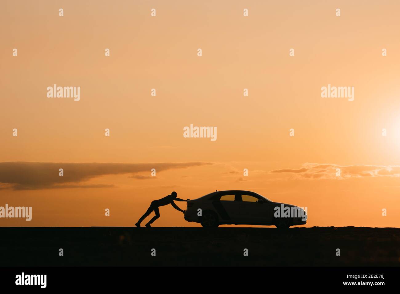 Silhouette of man driver pushing his car along on an empty road after ... Silhouette of man driver pushing his car along on an empty road after ...