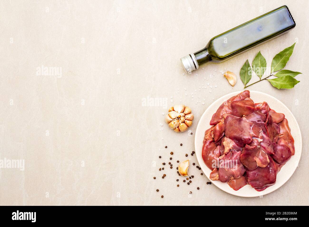 Raw chicken liver with spices on a stone background. Garlic, olive oil ...