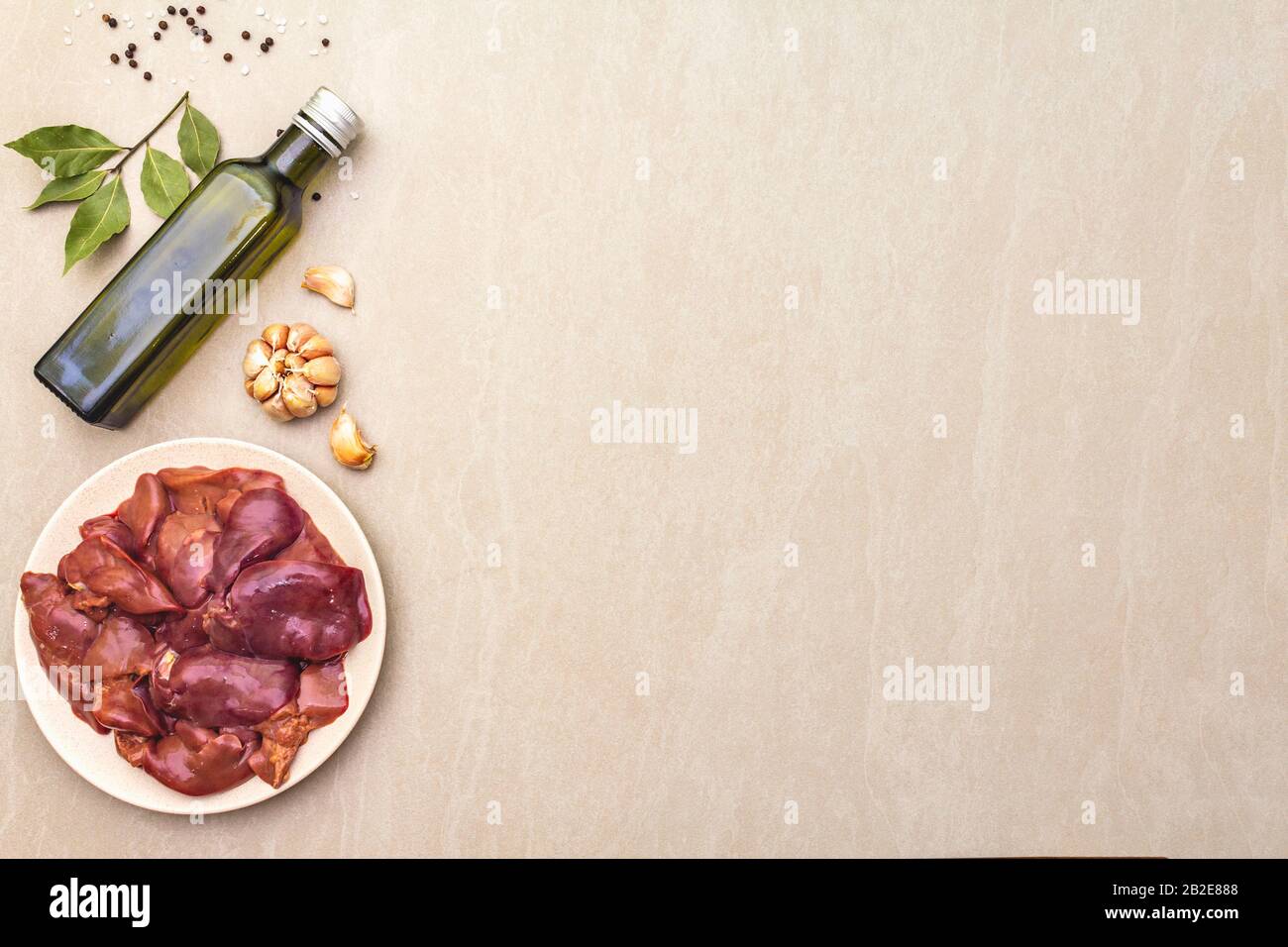 Raw chicken liver with spices on a stone background. Garlic, olive oil ...