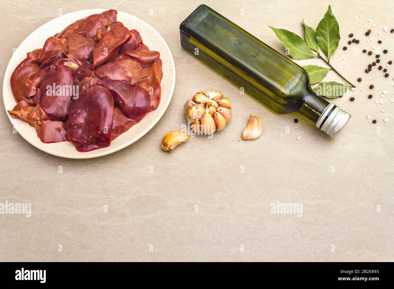 Raw chicken liver with spices on a stone background. Garlic, olive oil ...