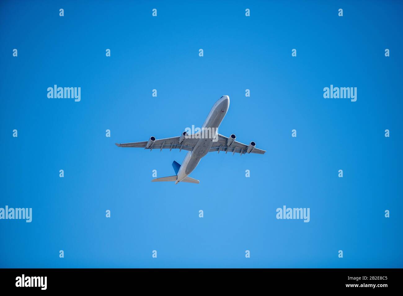 under belly of commercial passenger jet on cloudless blue sky Stock ...