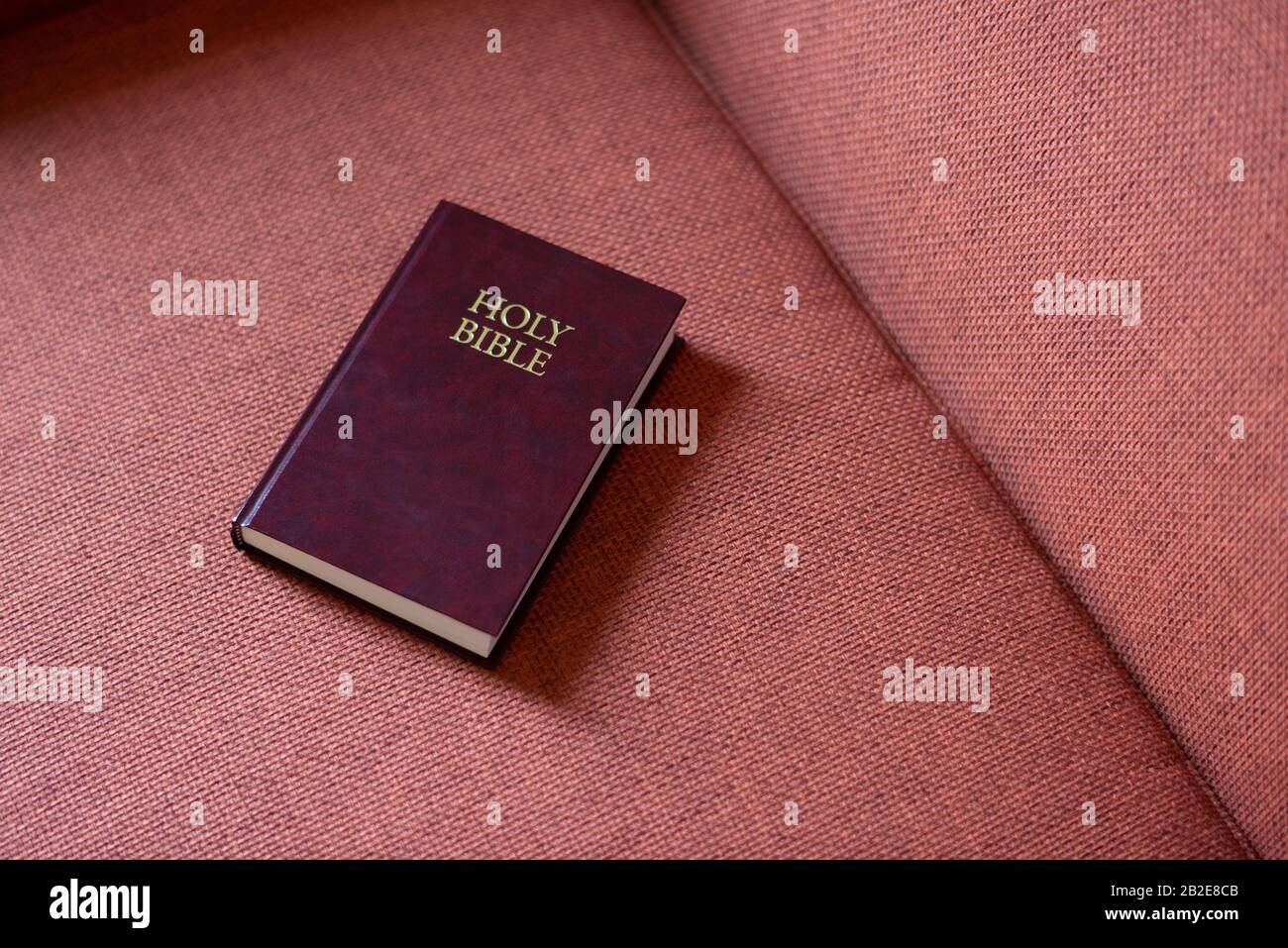 Holy Bible on coral colored chair in motel room Stock Photo - Alamy
