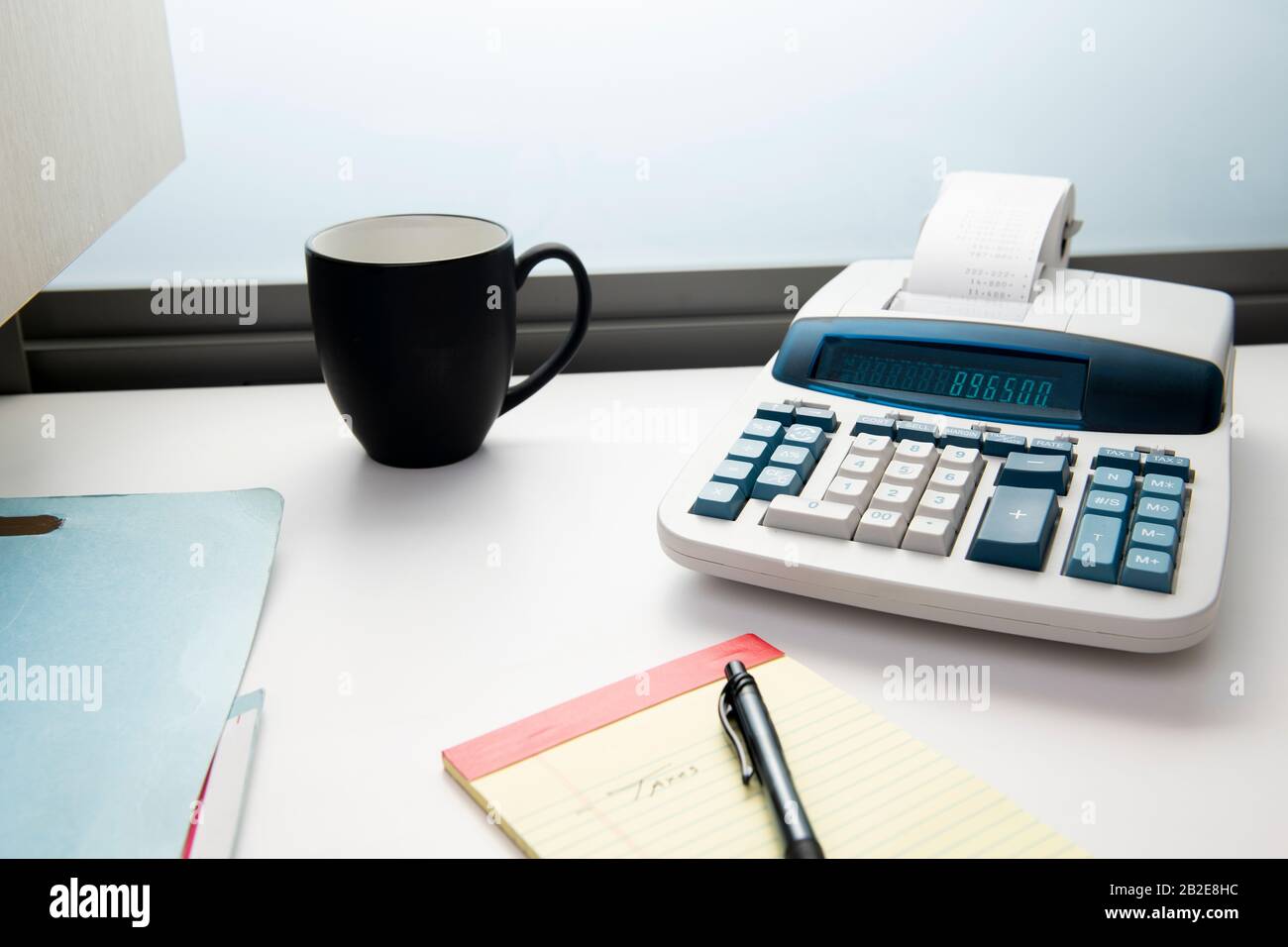 Adding machine with coffee cup, notepad, and filefolder on office desk ...
