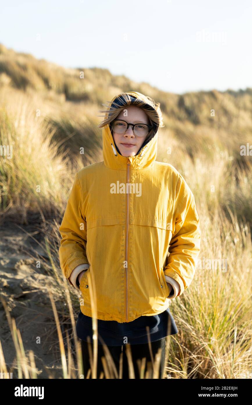 Tween standing in dunes covered in beach grass on the California coast ...