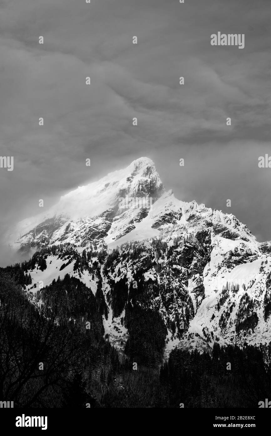 A snow-covered mountain peak on a windy day in the North Cascades Stock ...