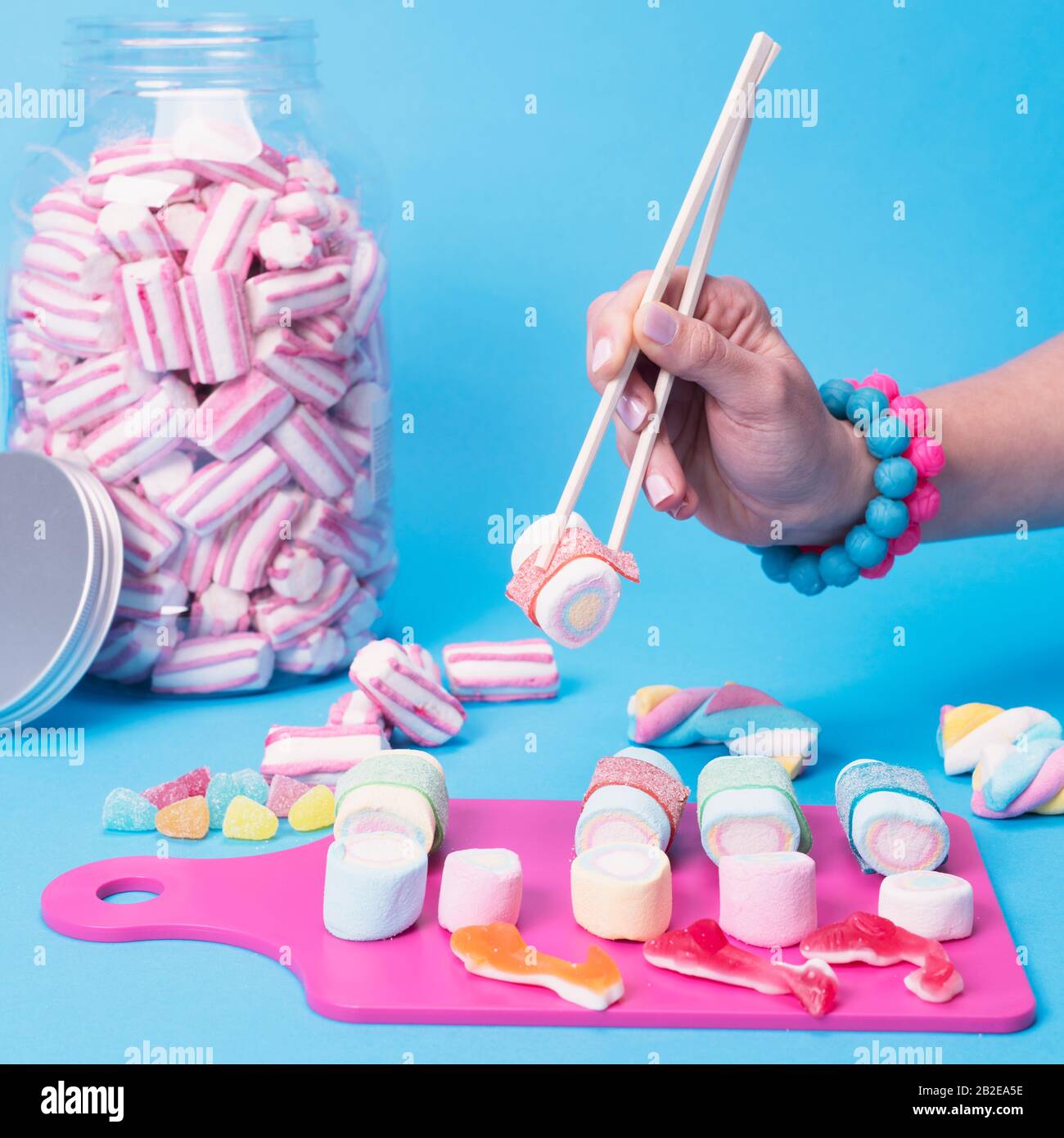Female hand using chopsticks with candy sushi Stock Photo - Alamy