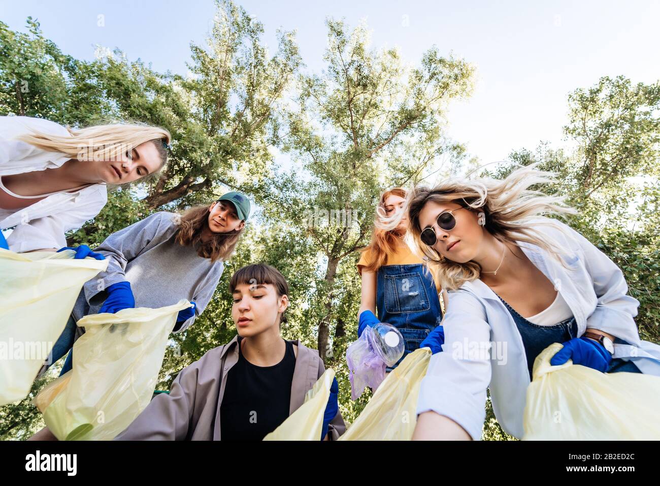 Group of activists friends throw a lot of garbage in a bag. Bottom-up ...