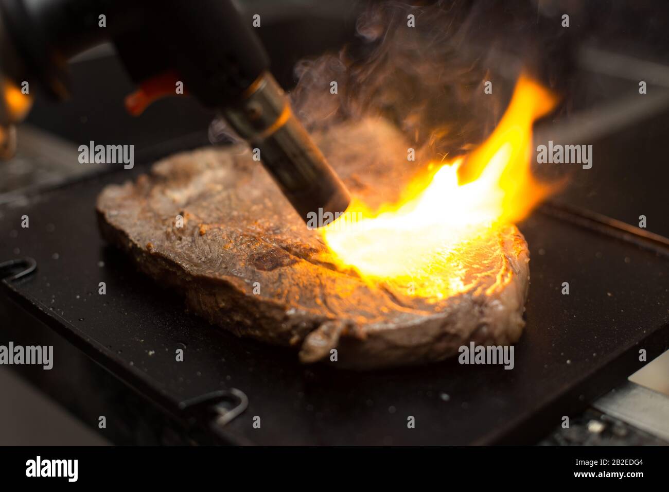 Steak being torched Stock Photo - Alamy